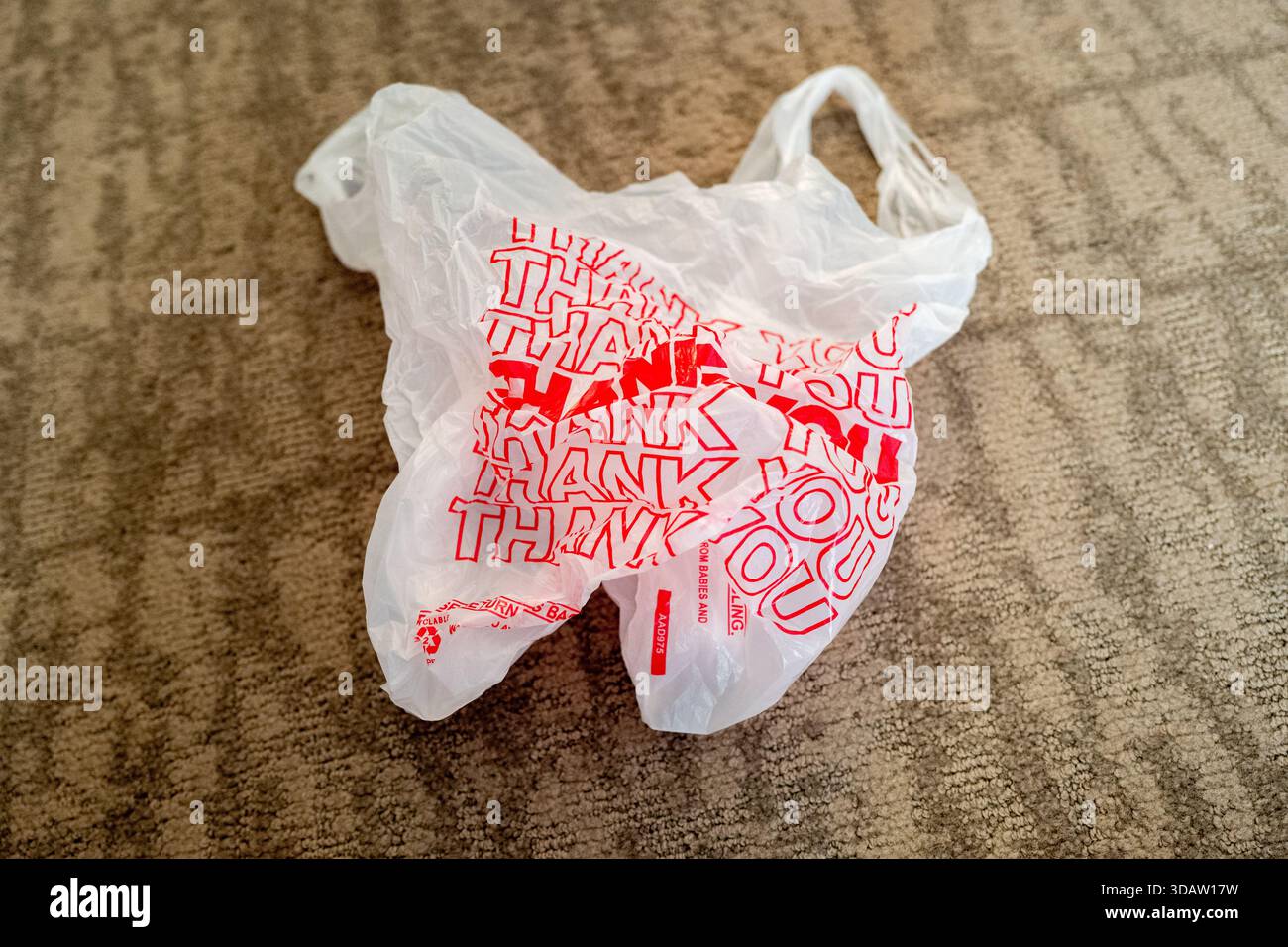 A single-use plastic bag is seen on the ground on a carpeted surface ...