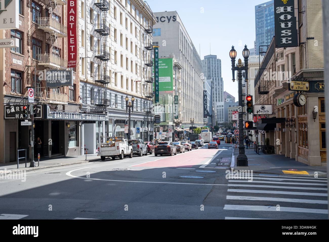 Daytime street scene with vehicles, crosswalk, and storefront signs ...