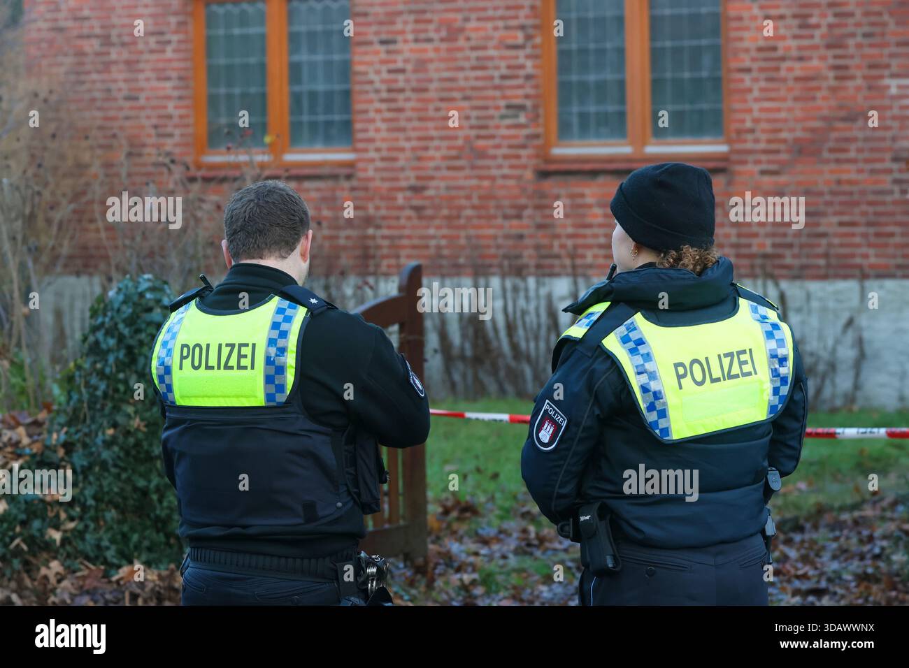 12 December 2025, Hamburg: Police officers are standing in front of a ...