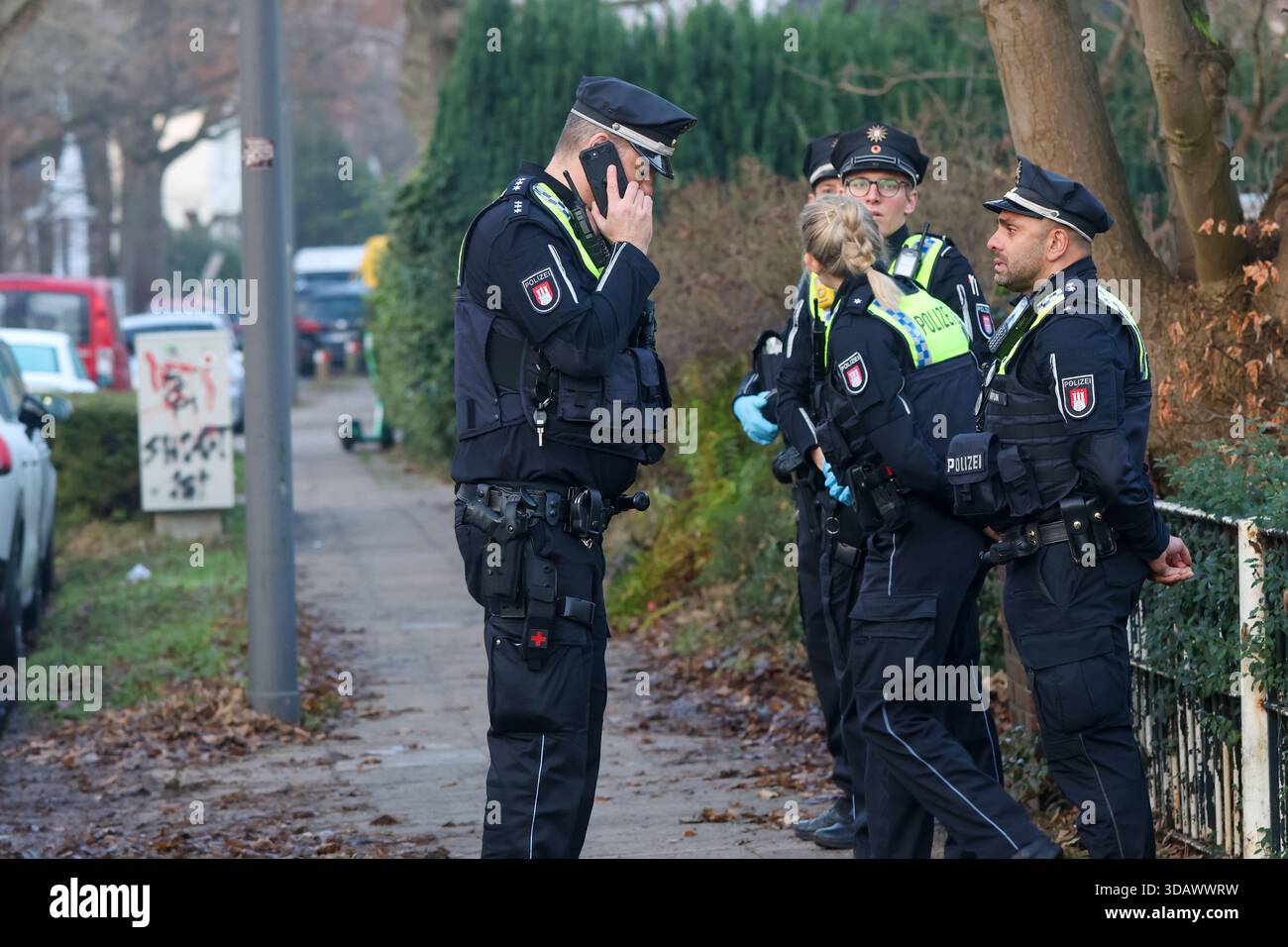 12 December 2025, Hamburg: Police officers are standing in front of a ...