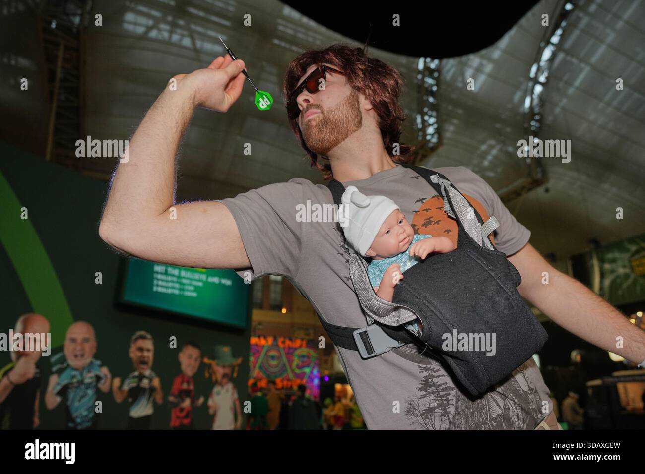 A fan in the dress with a baby, plays dart as he watches the World ...