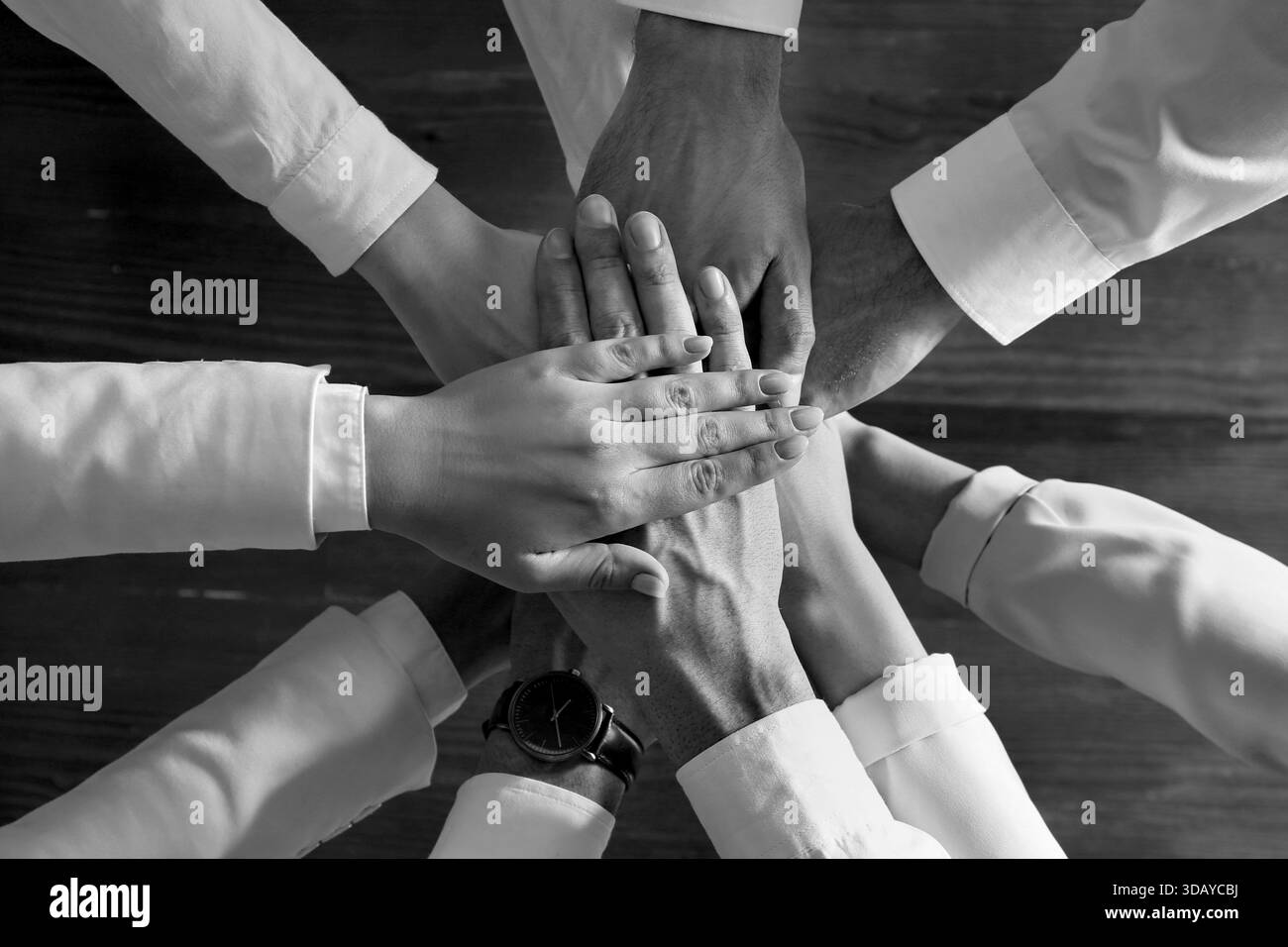 Group of people stacking their hands together, top view. Black-and ...