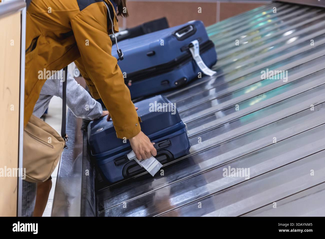 Tourist retrieving luggage from the baggage carousel in an airport ...