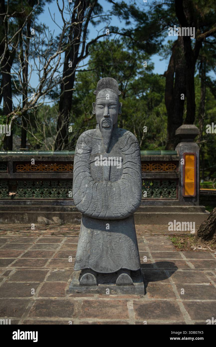 Timeless stone mandarin guardian statue in courtyard setting amid trees ...
