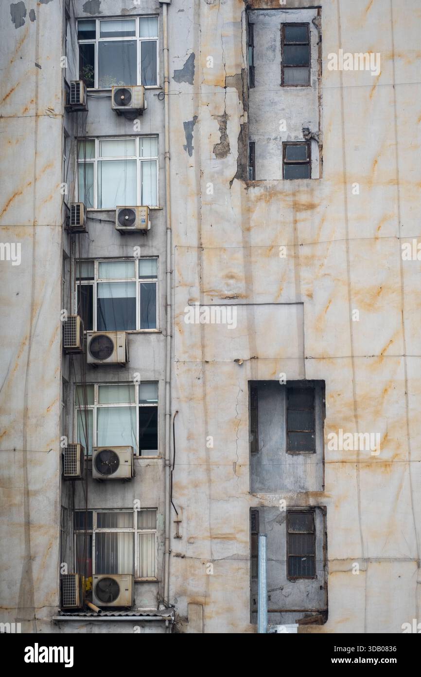 Weathered old apartment building facade with multiple air conditioning ...