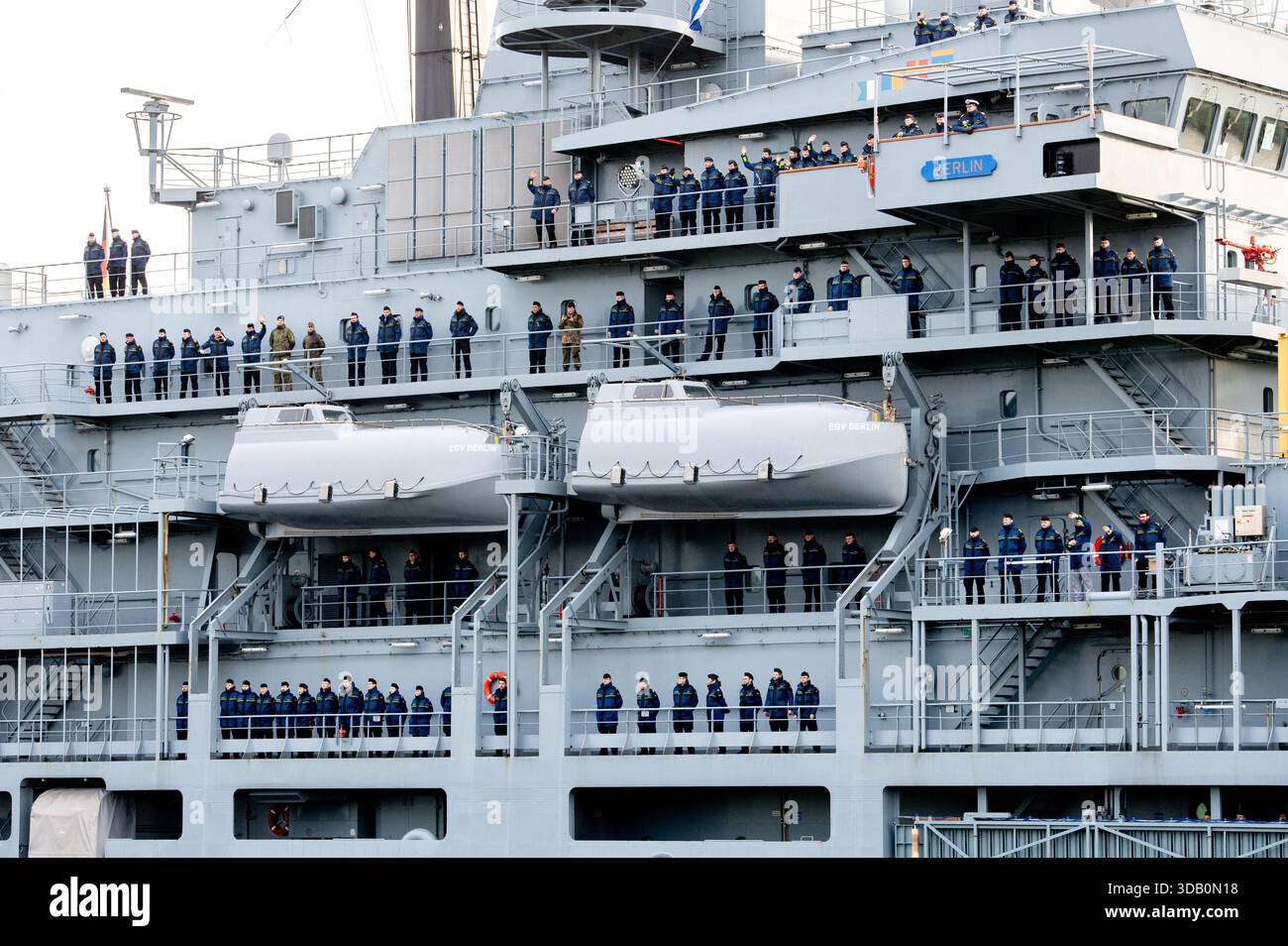13 December 2025, Lower Saxony, Wilhelmshaven: Crew members stand on ...