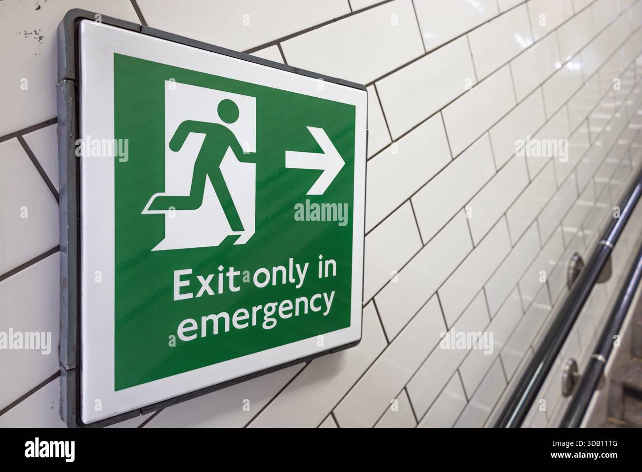 Green Emergency Exit Sign on White Tiled Subway Wall Stock Photo - Alamy