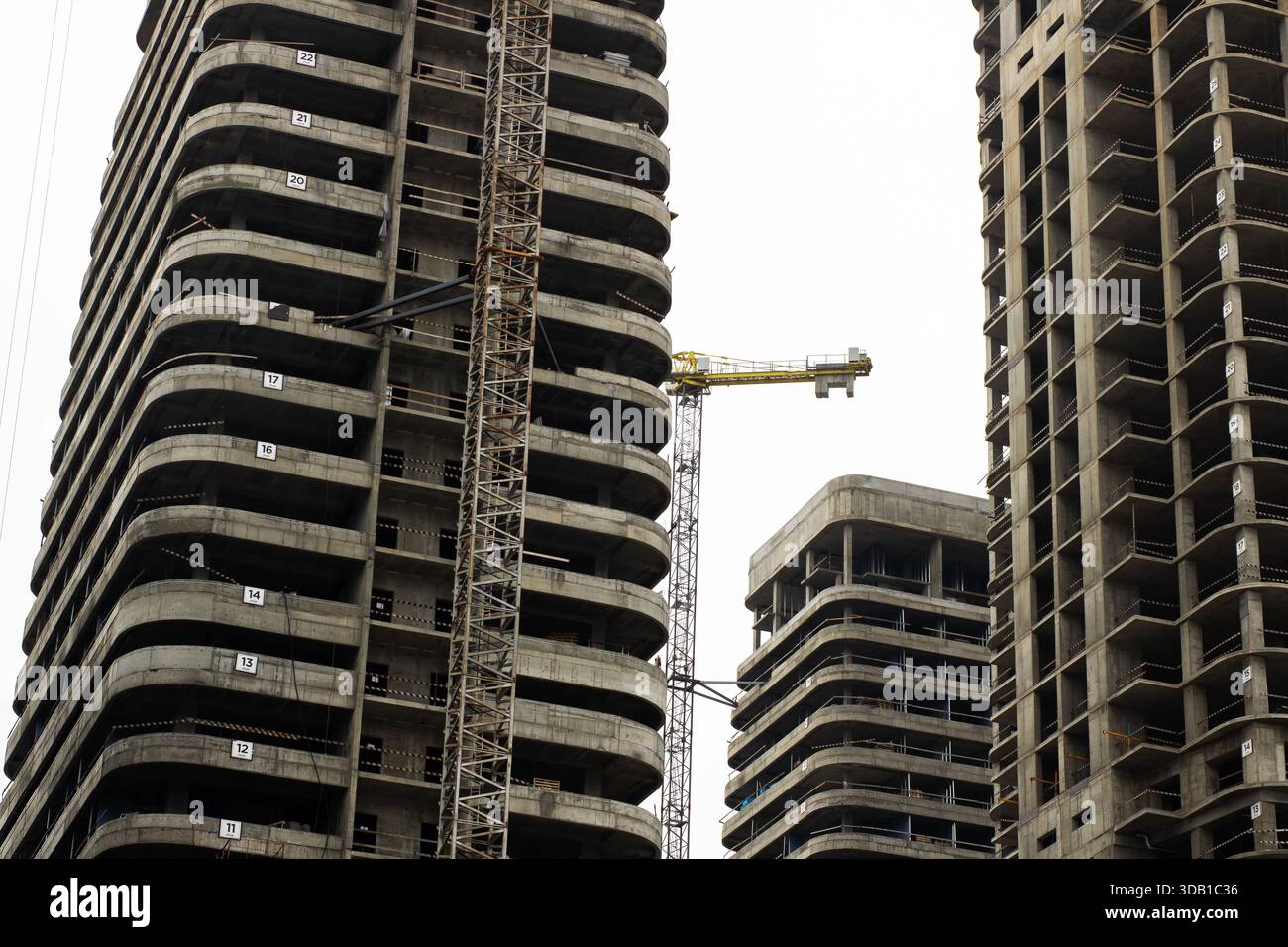 curved balcony towers under crane, raw concrete shells with repeating ...