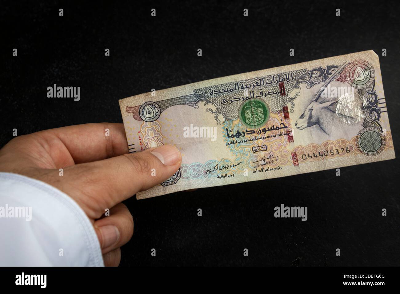 Hand holding UAE dirham banknotes, featuring Sheikh Zayed portrait and ...