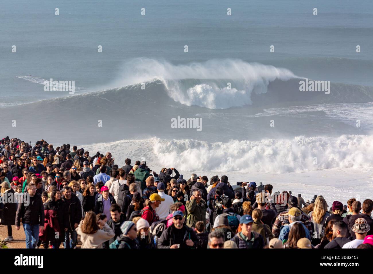 Spectators gather on the cliffs as massive waves crash below during the ...