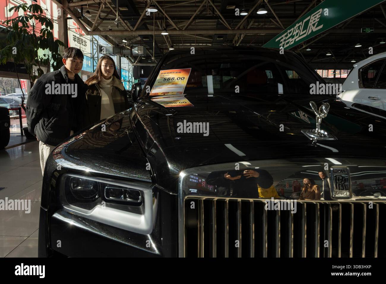 Visitors look at a second hand luxury car for sale in Beijing on Friday ...