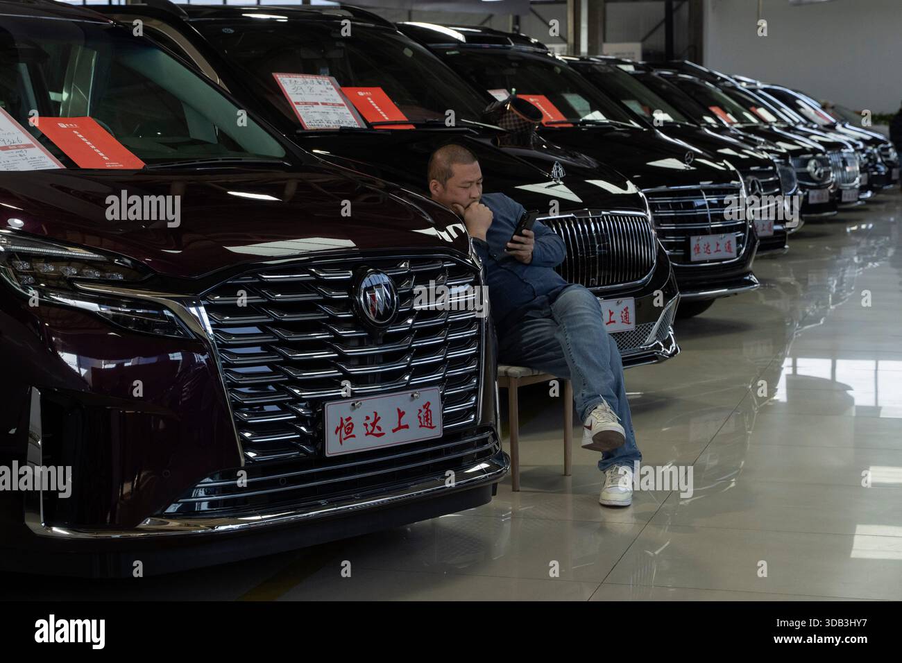 A man rests near second hand luxury cars for sale in Beijing on Friday ...