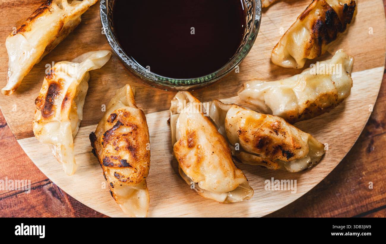 Pork gyoza arranged in a perfect circle around a soy sauce container on ...