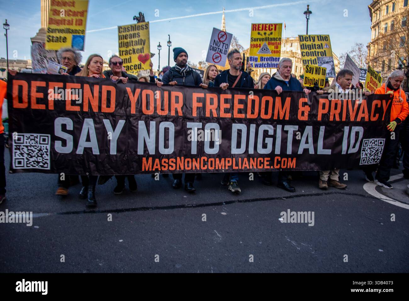 Protestors hold a large banner and placards during the "Say No To ...