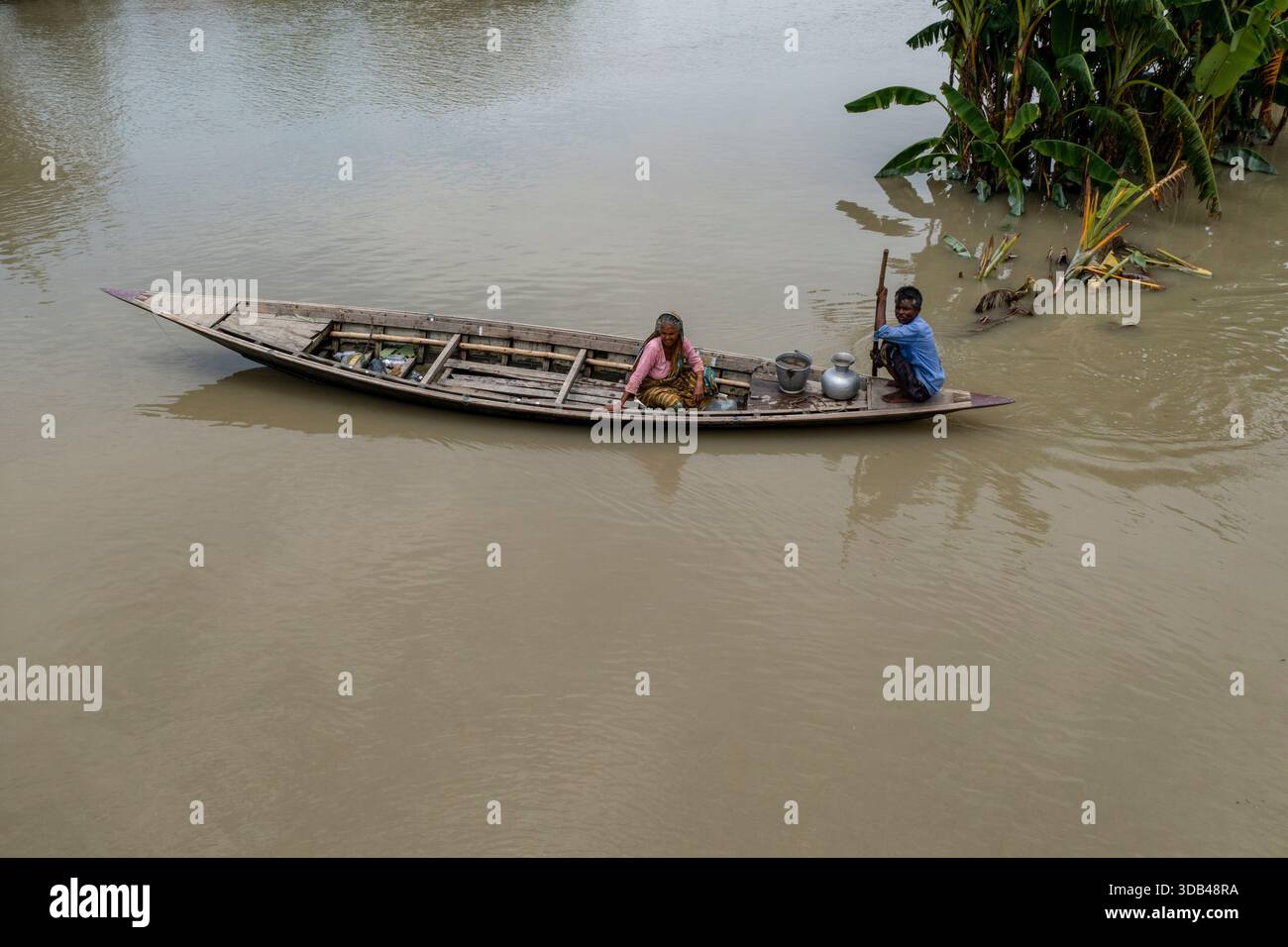 A couple carry safe drinking water on a boat as they return home amid a ...