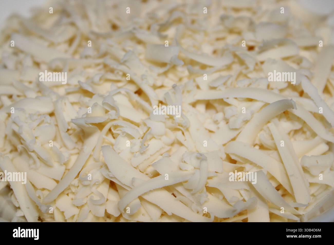 A bowl contains shredded cheese ready for use in cooking. Bits of ...