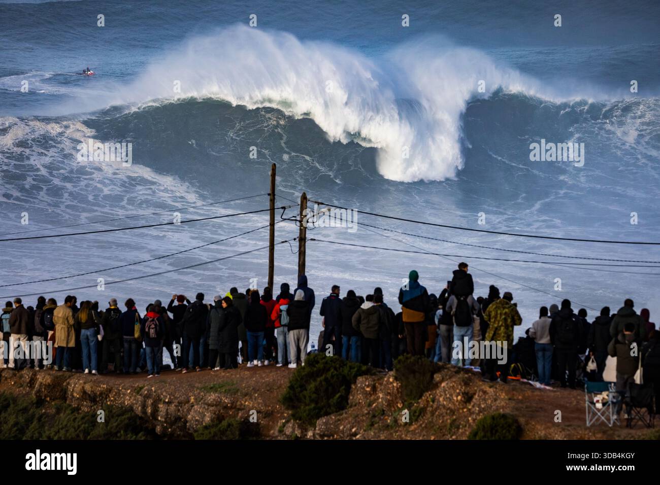 An empty wave breaks in front of the spectators watching from the cliff ...