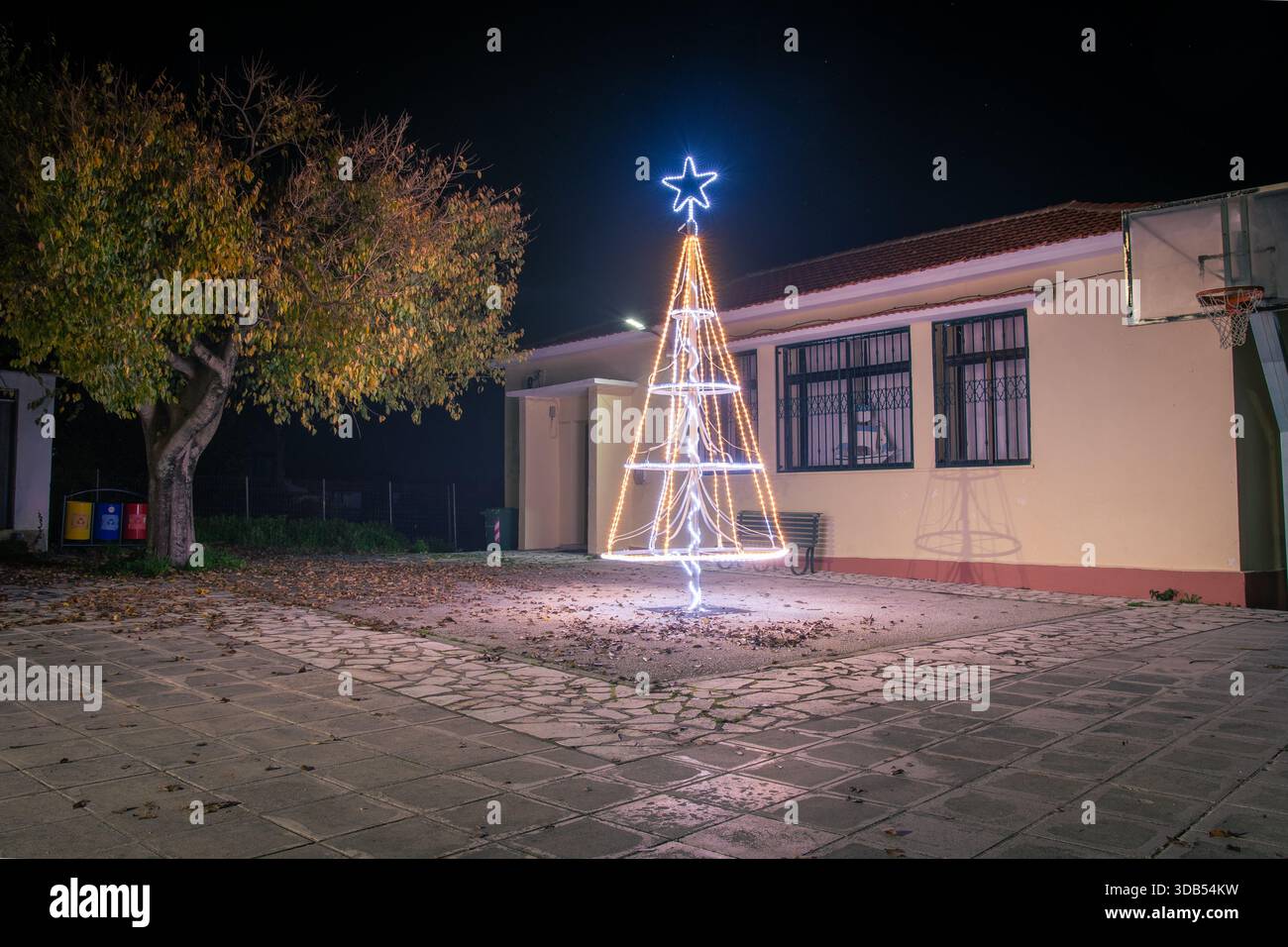Modern wire Christmas tree with star illuminated at night in front of ...