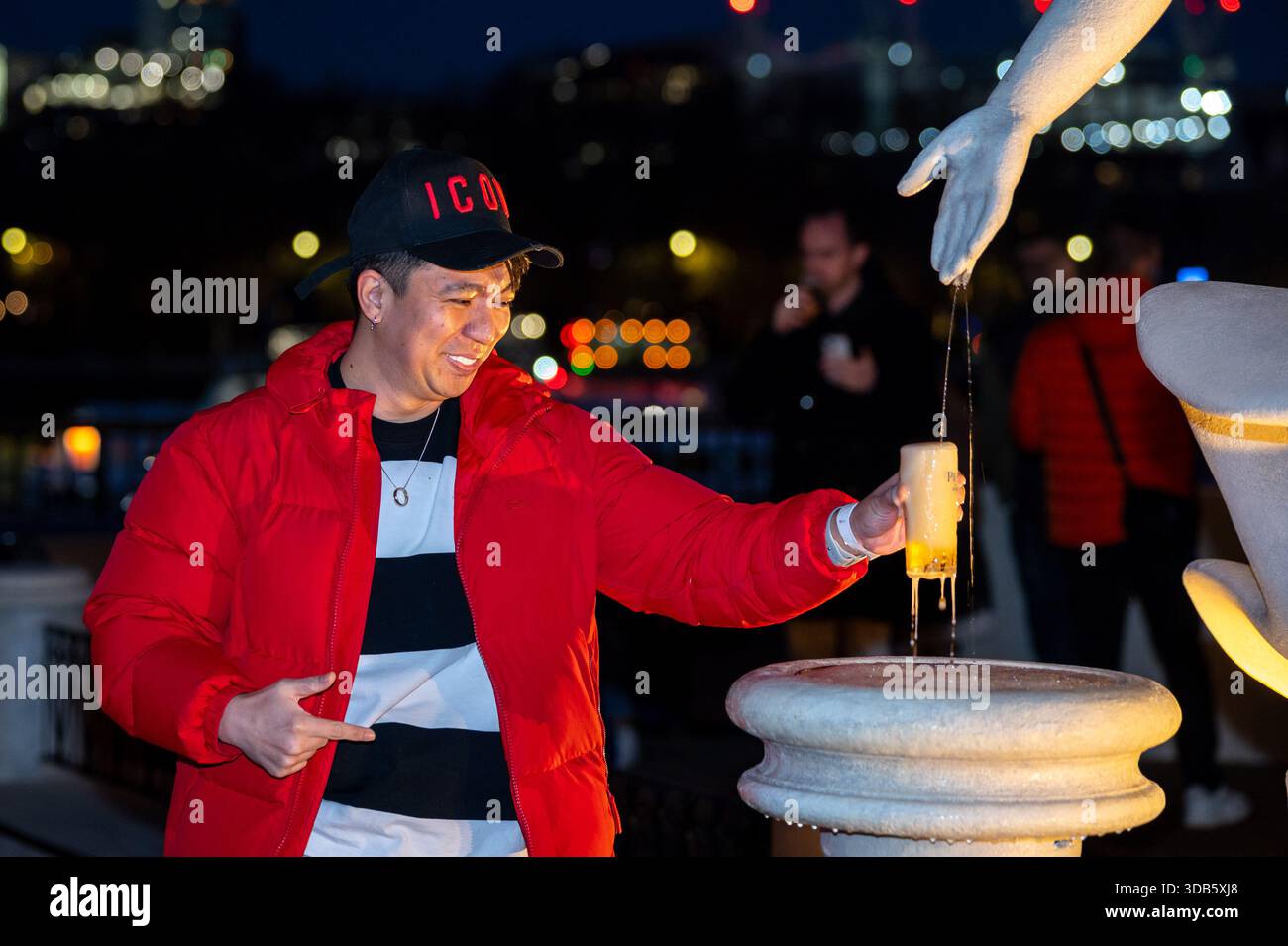 A man seen pouring beer in a glass. Visitors gathered around a ...