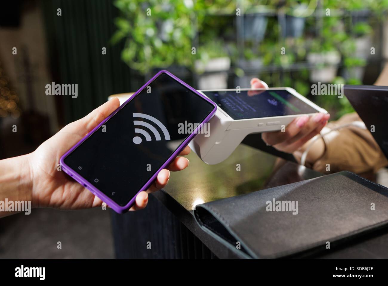 Customer uses smartphone NFC tap to pay on handheld POS reader at cafe ...
