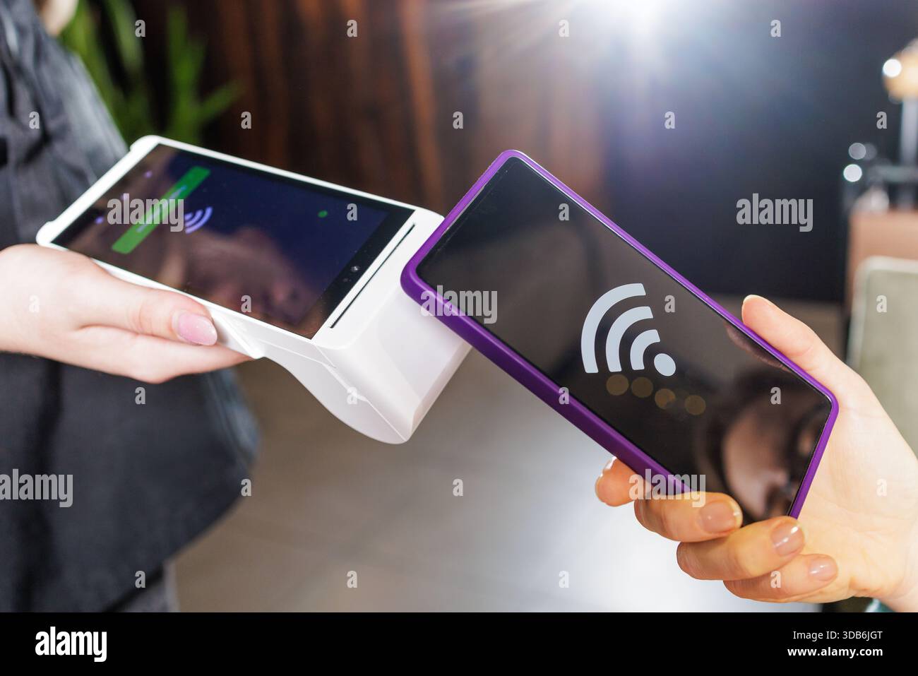 Close up of smartphone tap to pay using NFC on handheld POS terminal at ...
