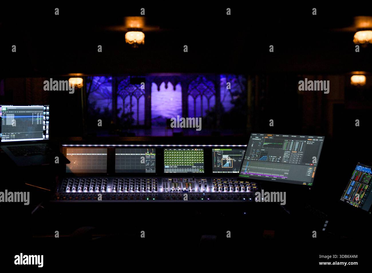 Professional digital sound mixing console illuminated in dark theater ...