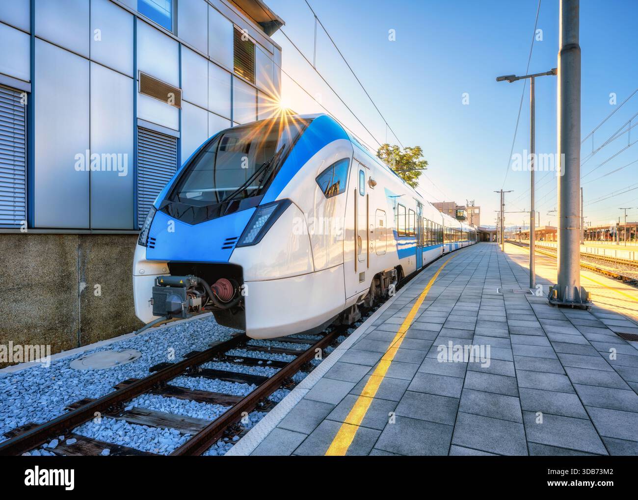 High-speed blue passenger train at railway station at sunset Stock ...