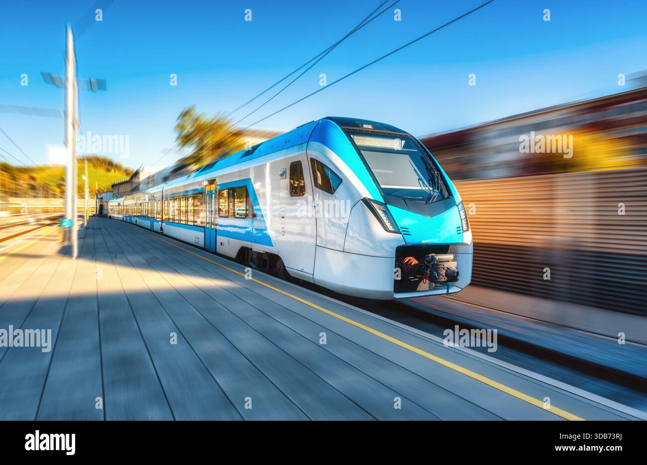 High-speed blue passenger train moving at railway station Stock Photo ...