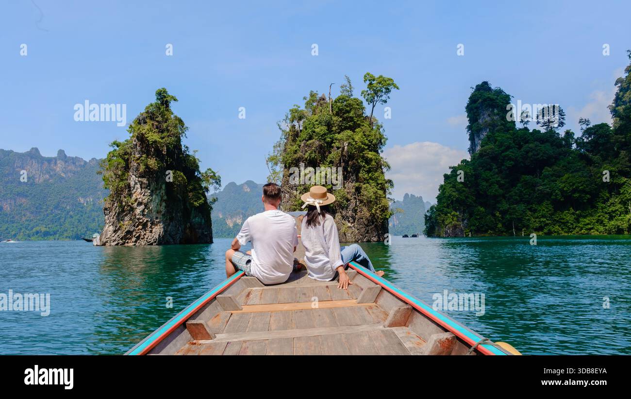 Couples enjoy a tranquil boat ride on Cheow Lan Lake, surrounded by ...
