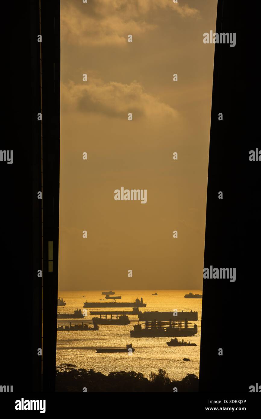 Orange hue sky with filled with industrial ships in silhouette along ...