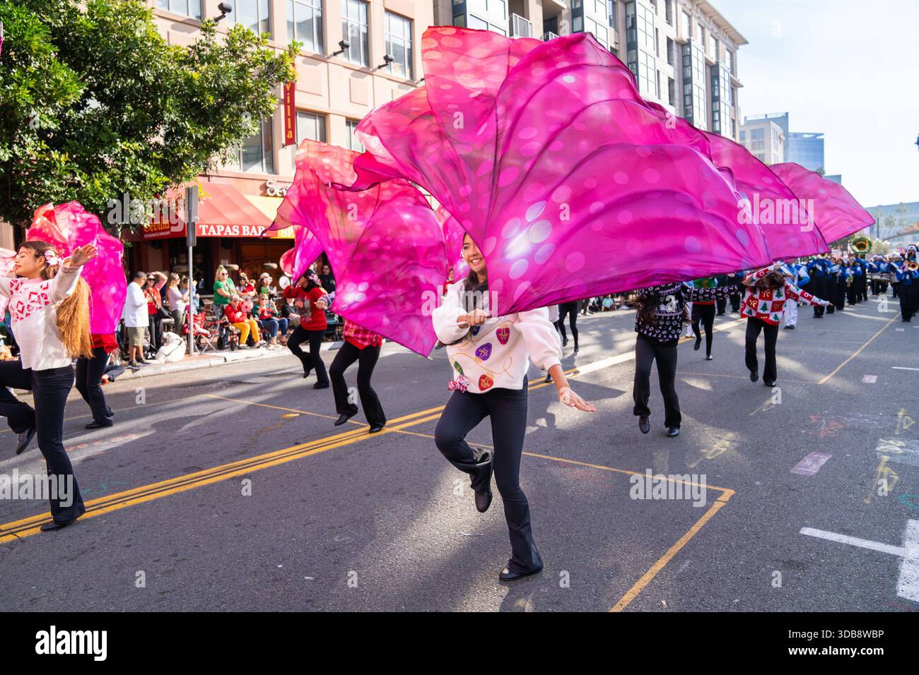 Performers wave large pink flags as they dance along the parade route ...