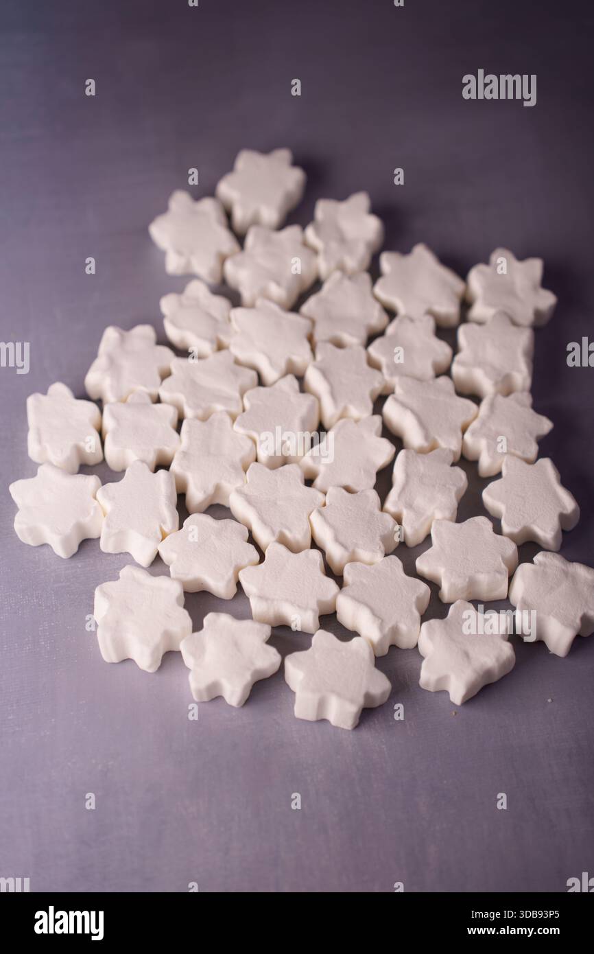 cluster of star-shaped white candies arranged randomly on smooth gray ...