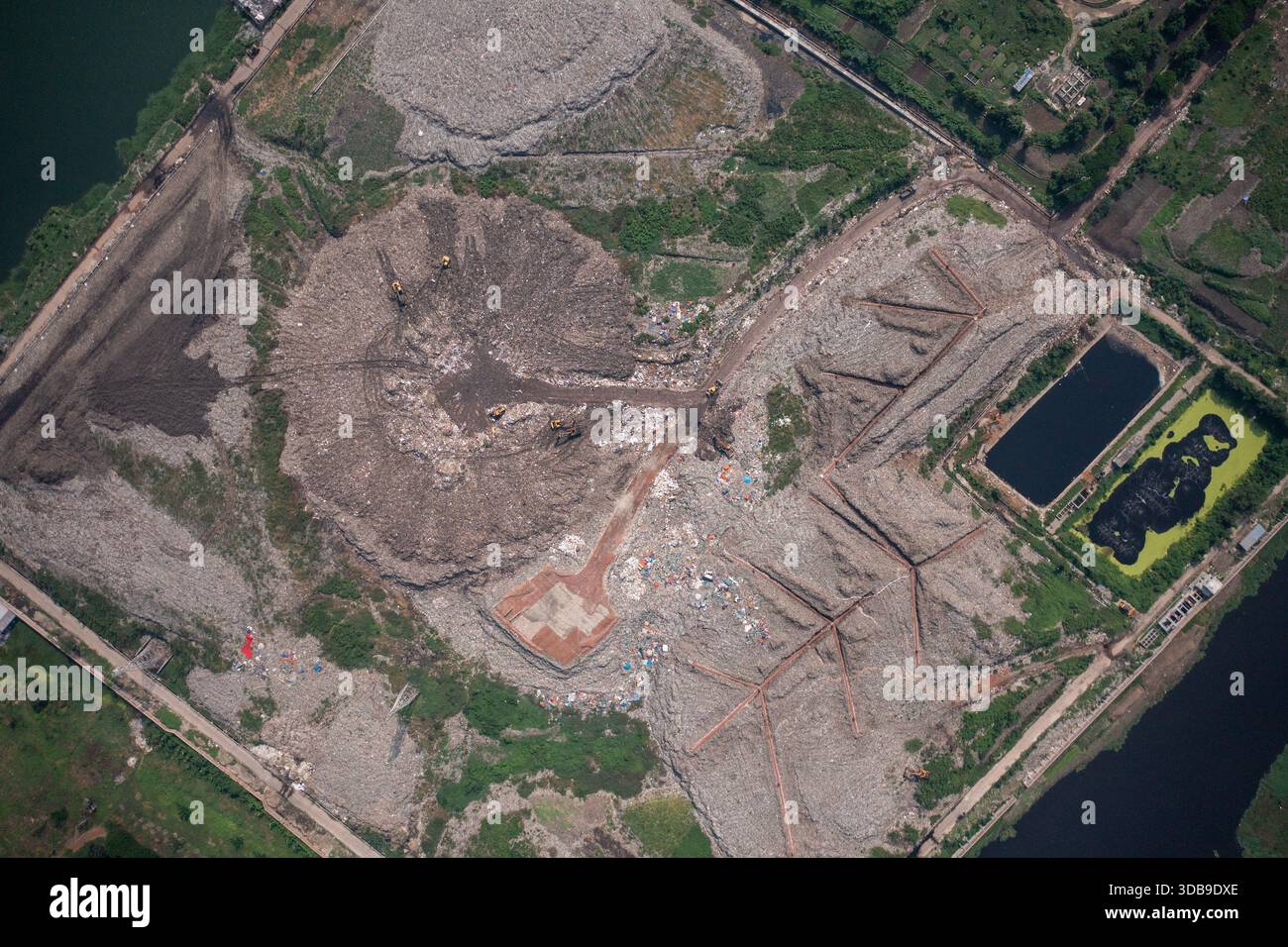 Aerial view of a vast landfill with piles of waste, dark patches, and ...
