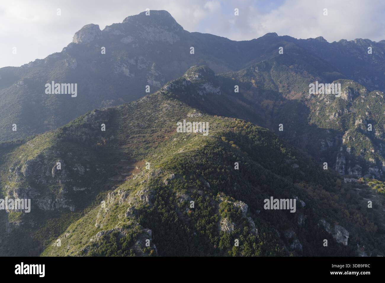 Aerial view of rugged, verdant mountains rise sharply, their slopes ...