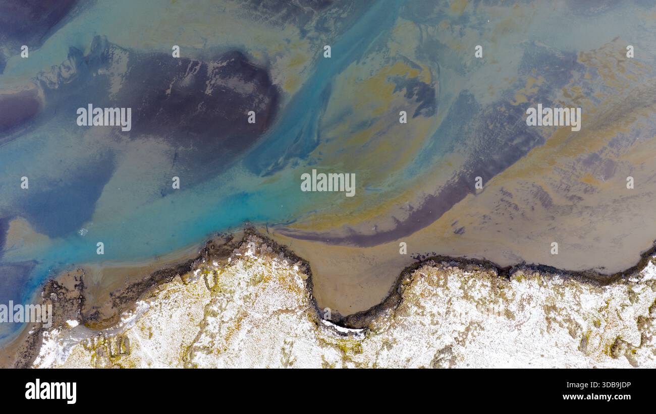 Aerial view of the coastline where the turquoise waters meet the snowy ...