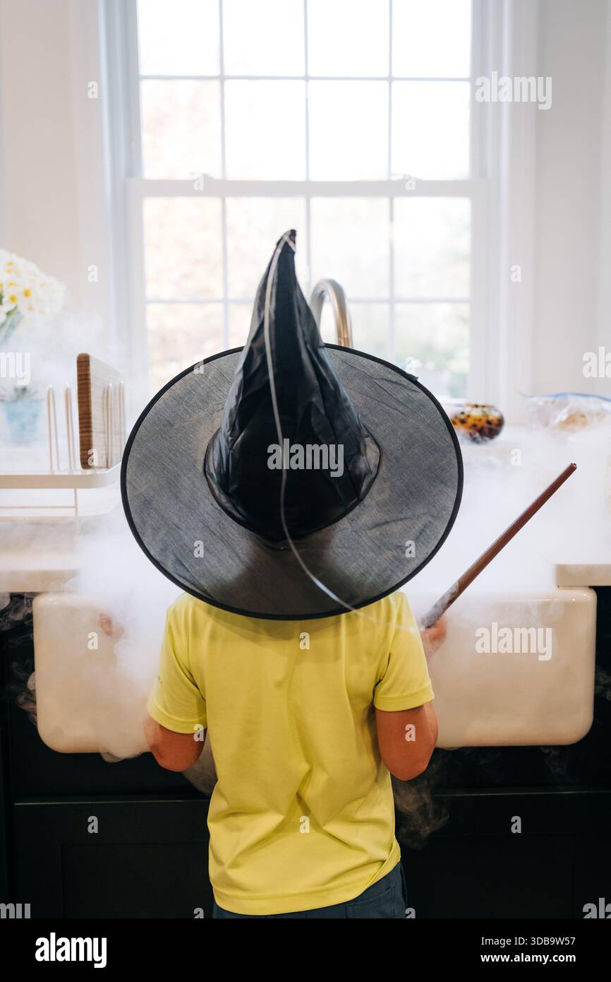 Child wearing witch hat casting magic spell in kitchen Stock Photo - Alamy