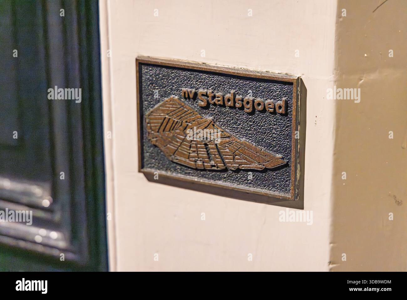 Close-up of a bronze plaque on a wall in Amsterdam with the text "nv ...