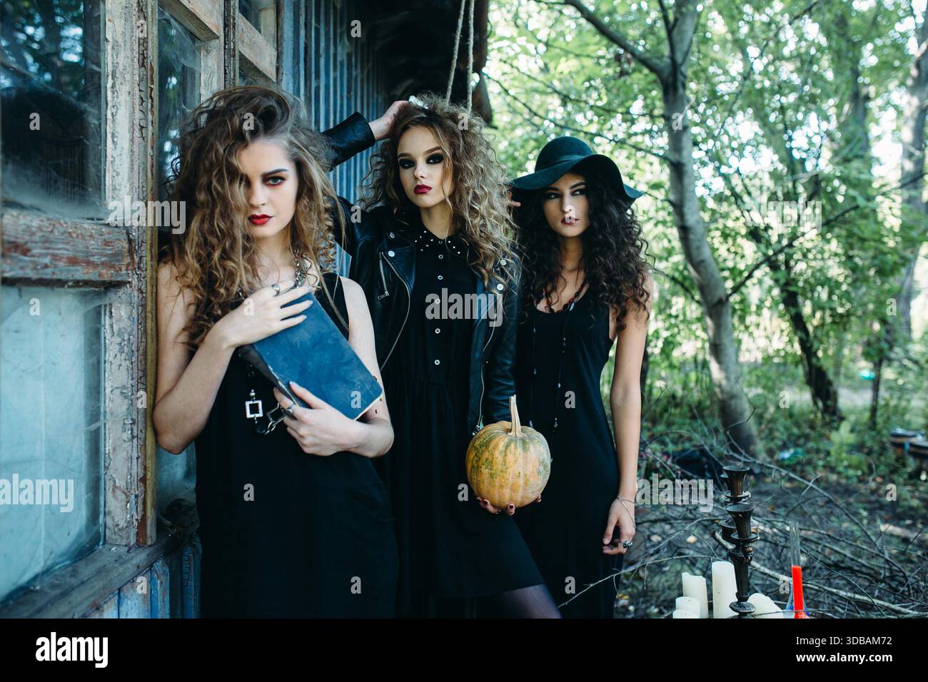 three vintage women as witches, poses near an abandoned building on the ...