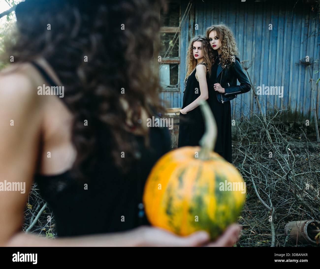 three vintage women as witches, pose in front of an abandoned building ...