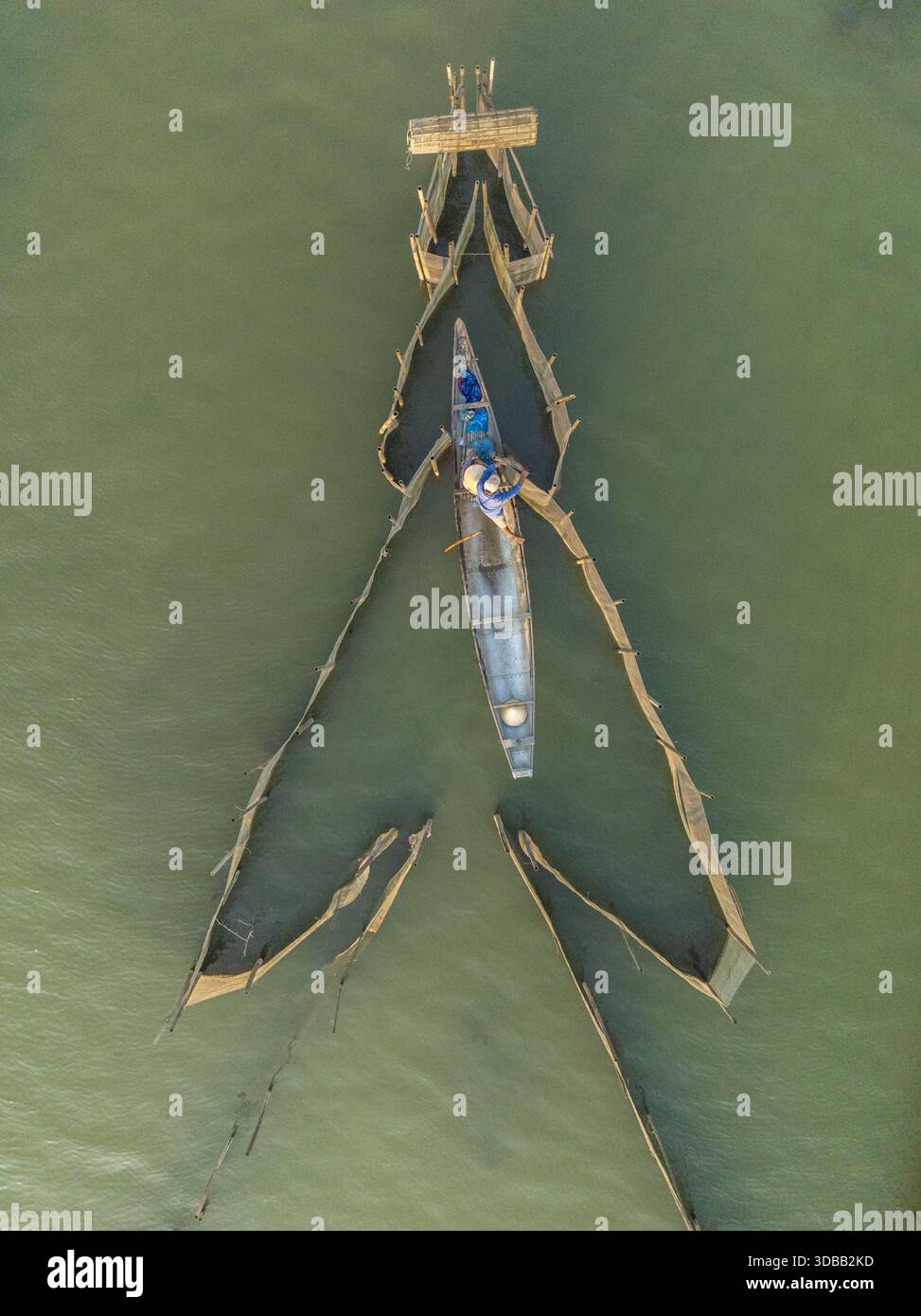 Aerial view of a lone fisherman in a narrow boat navigating through a ...