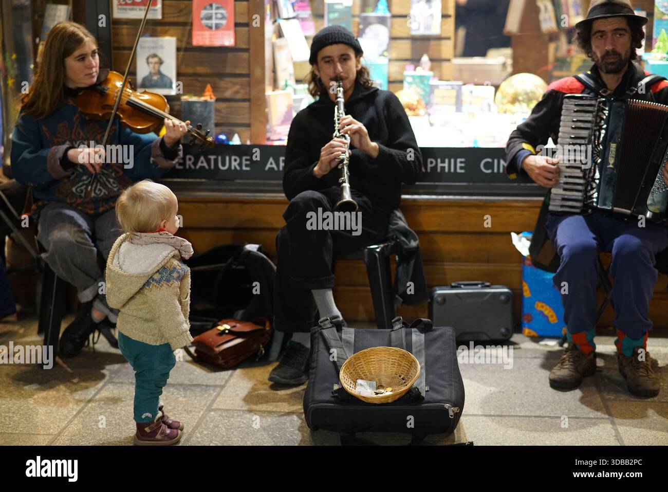Child standing in front of three street musicians playing violin ...