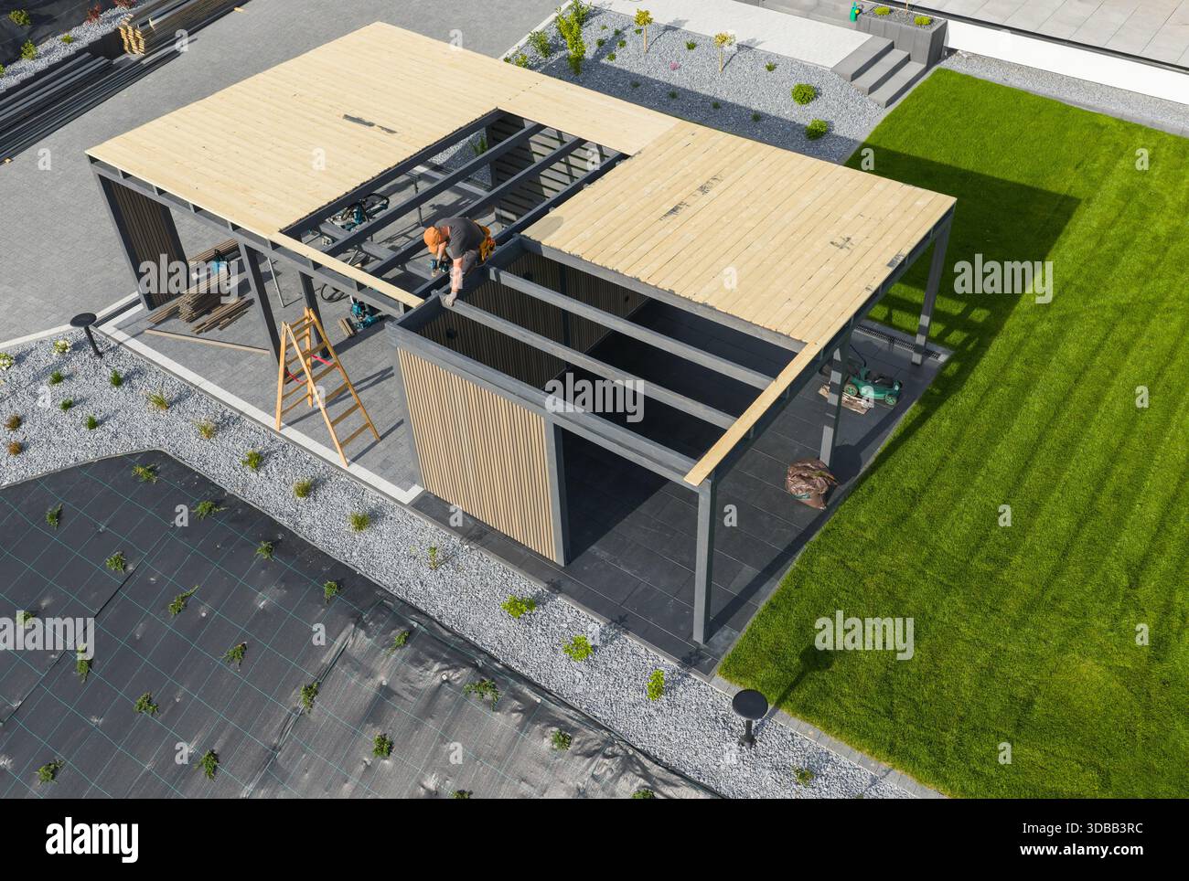 Two workers are installing a roof on a new structure in a backyard ...