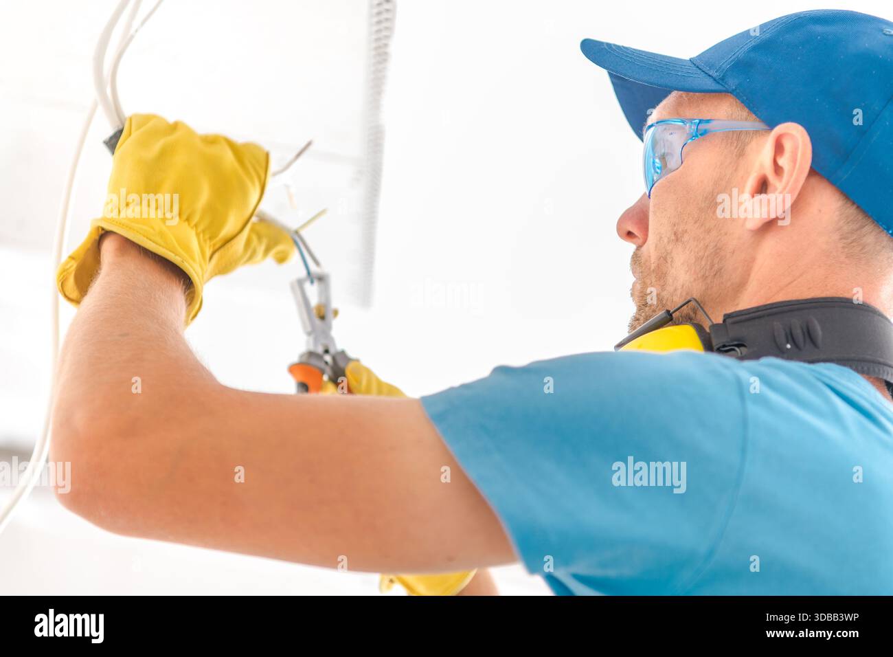 A worker uses tools to handle electrical wires while wearing gloves and ...