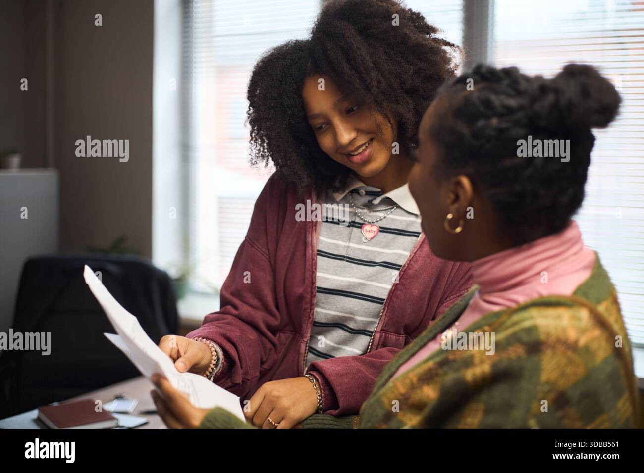 Young Black woman standing in office holding documents, smiling and ...