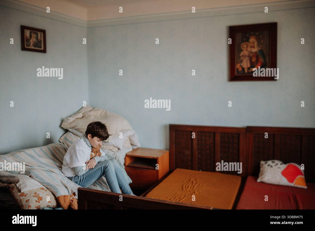 Sad orphan girl sitting alone in bedroom. Poverty concept Stock Photo ...