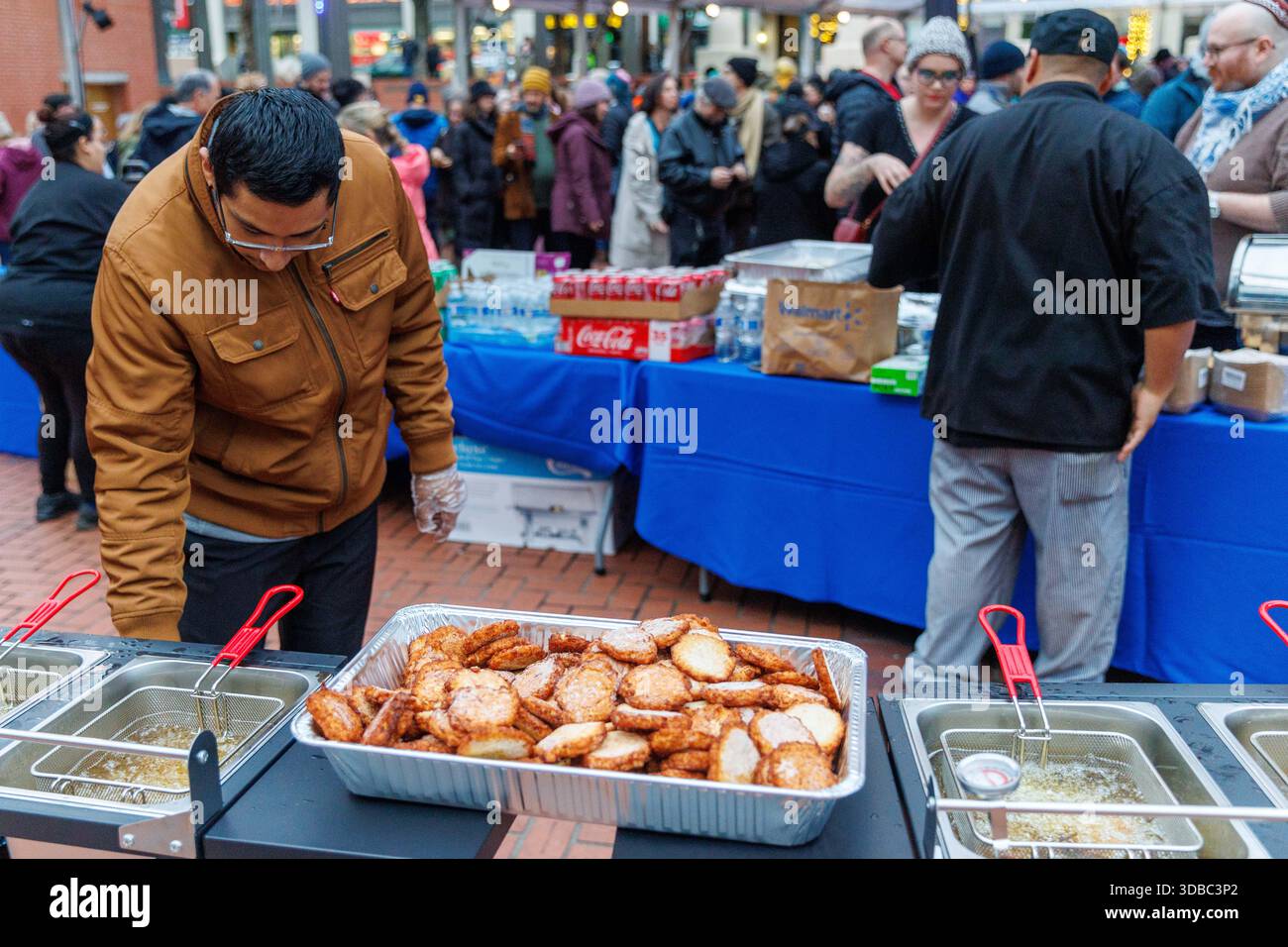 A man examines a tray of traditional latkes, a food often served at ...