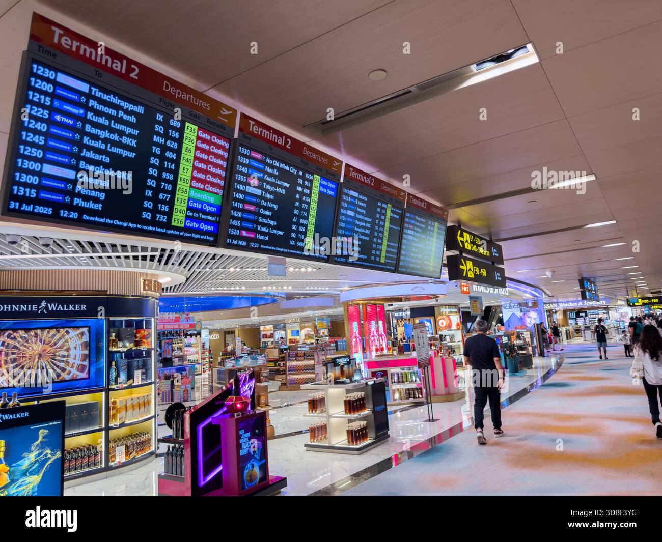 Departures board displaying flights at Terminal 2 while travelers walk ...