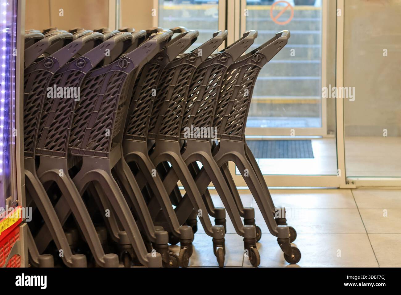 Group of gray plastic carts nested together near glass entrance with ...