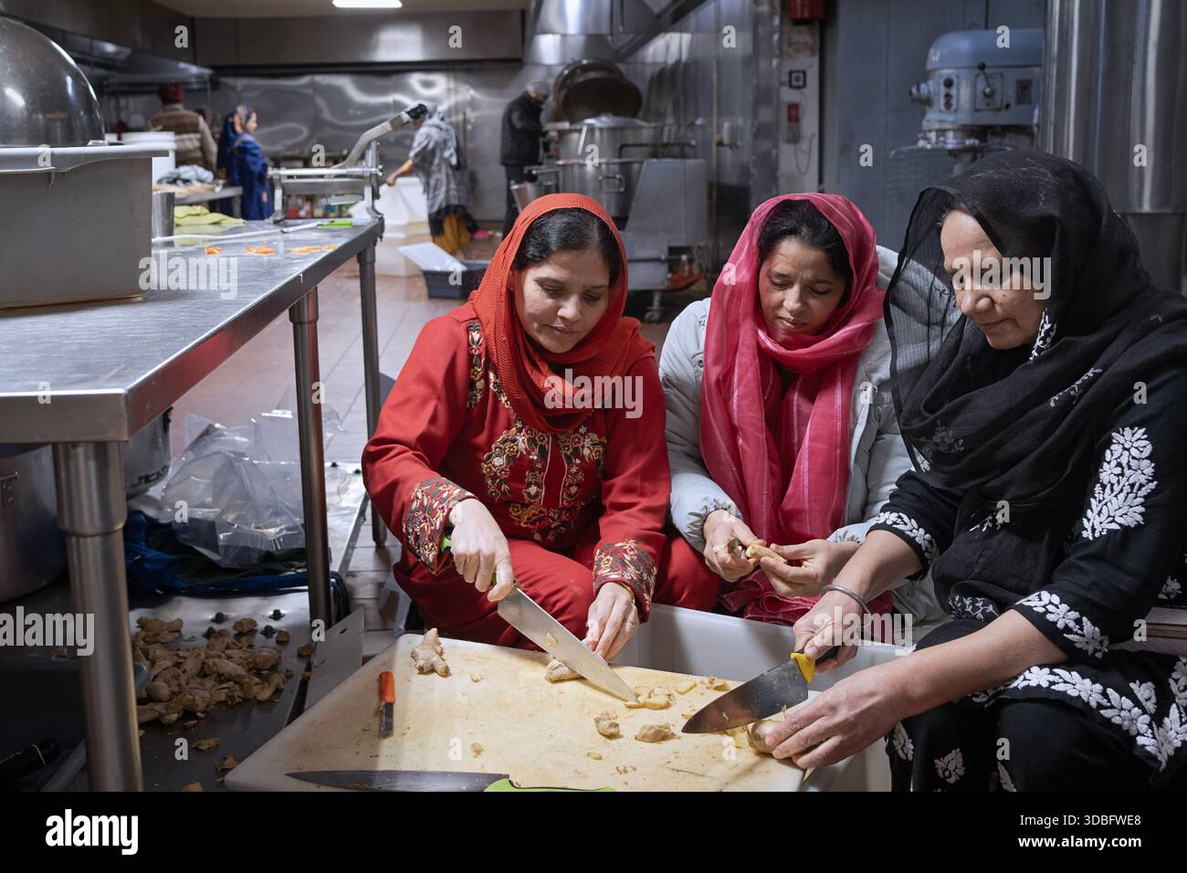 3 Sikh women volunteers cut ginger while preparing free meals for the ...