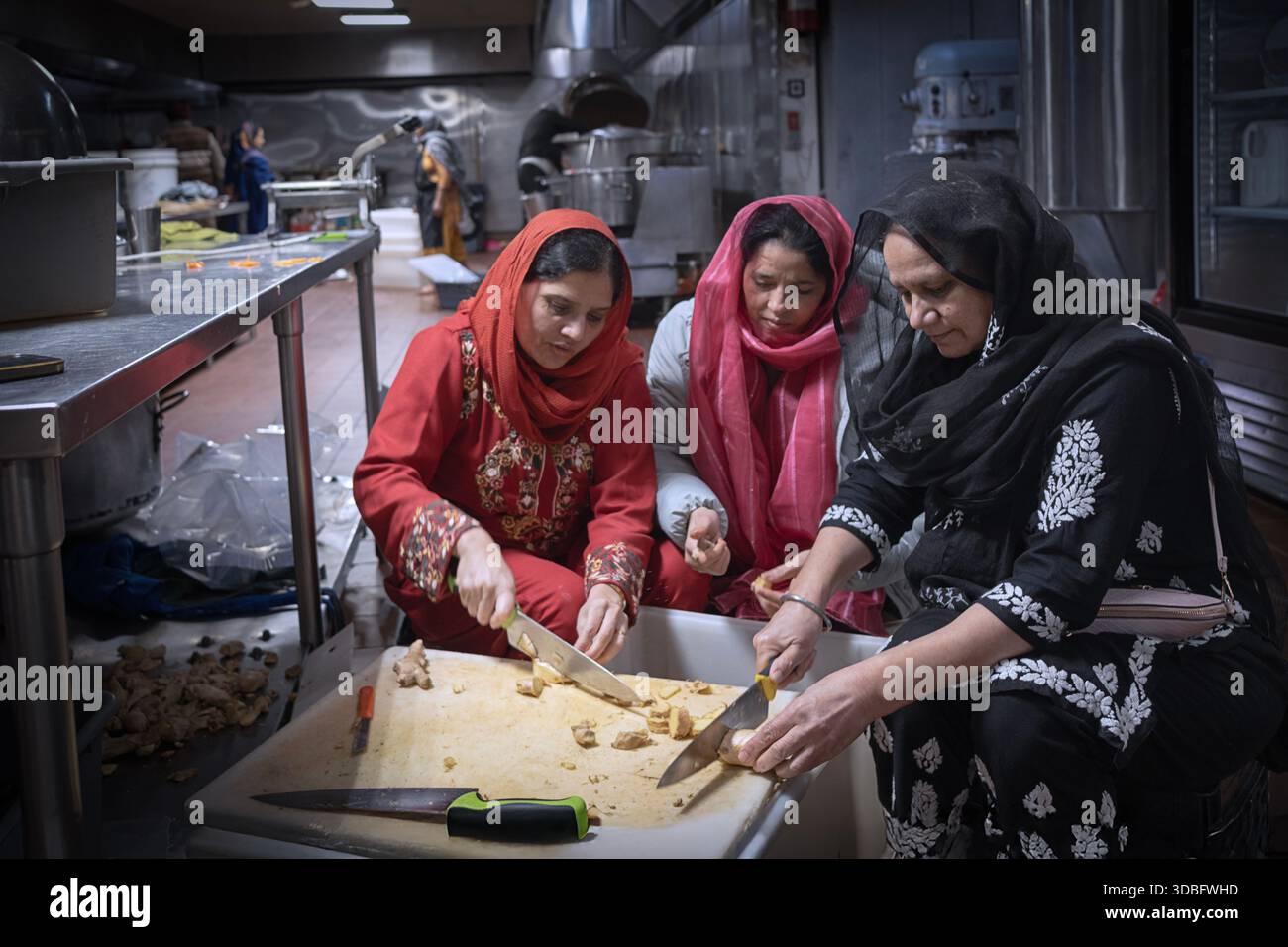 3 Sikh women volunteers cut ginger while preparing free meals for the ...
